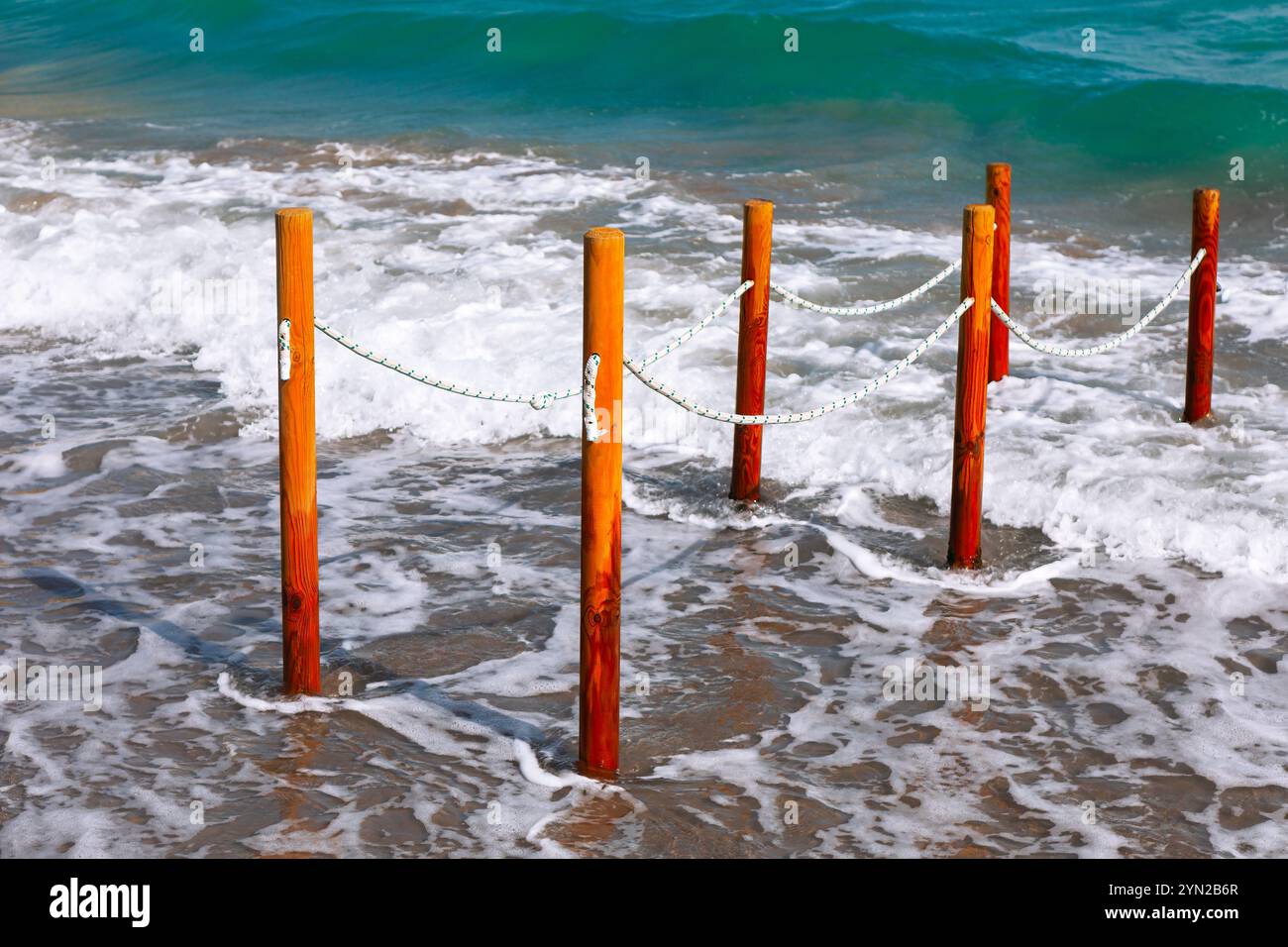 Beach where several wooden posts are embedded in the sand, connected by ...