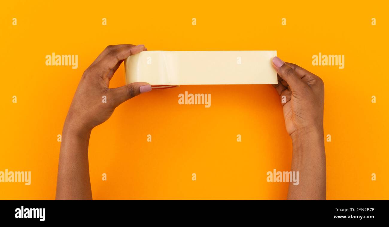 Roll of duct tape in female hands over orange background Stock Photo ...