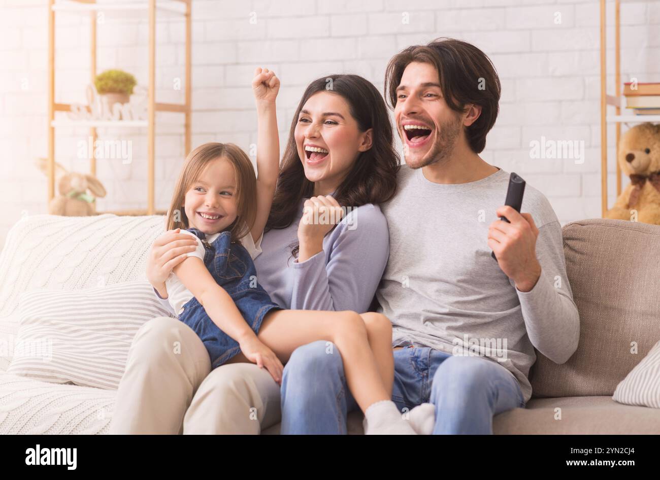 Family cheering sports together, watching football game on tv at home ...