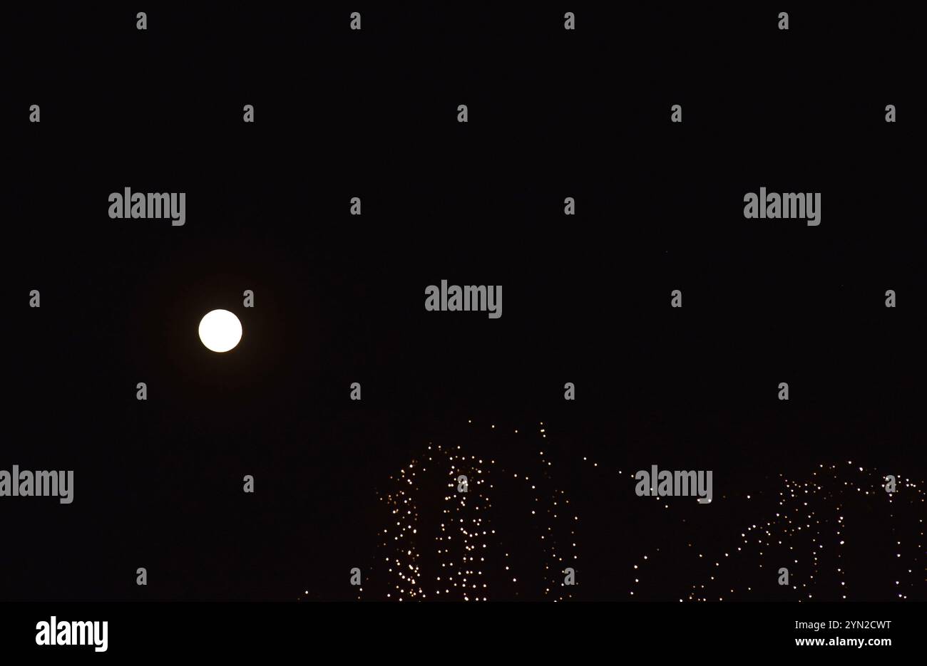 full moon floating on skyover light bulb decorating on tree in night ...