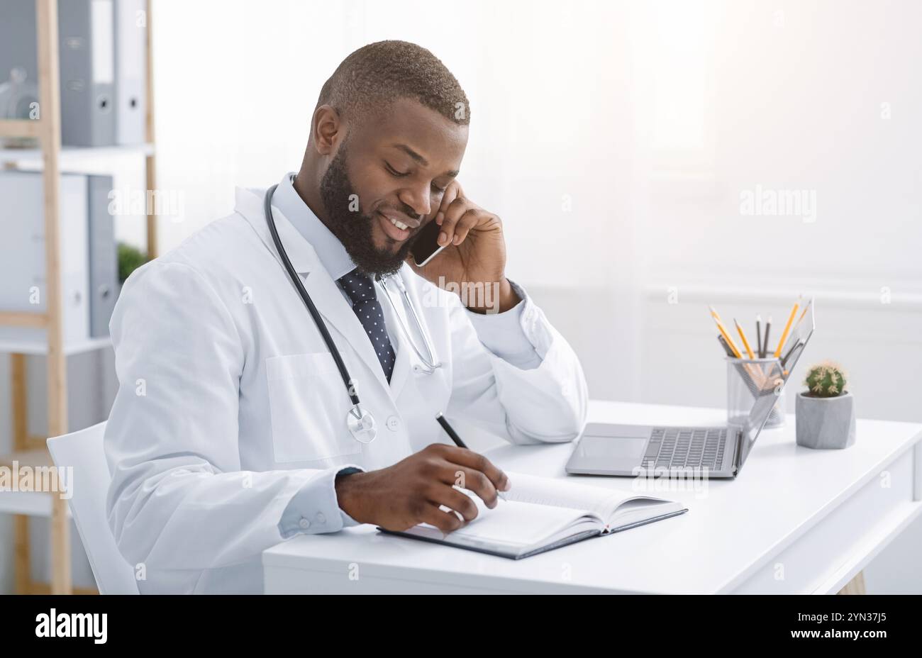 Young african doctor talking to patient on phone Stock Photo - Alamy