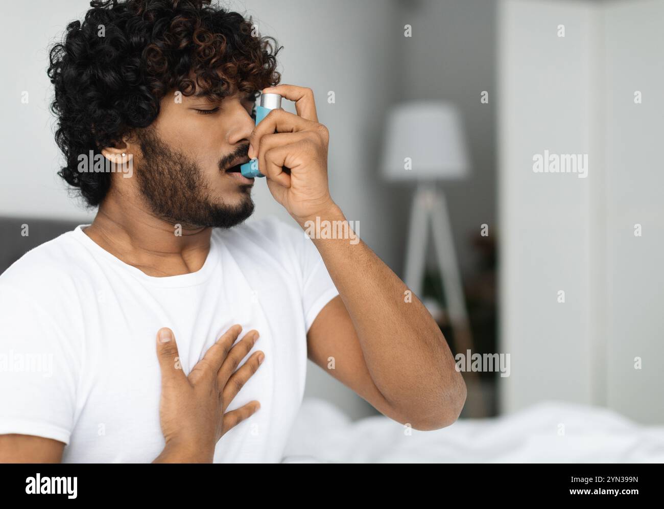 Indian guy suffering from asthma, using inhaler in bed Stock Photo - Alamy