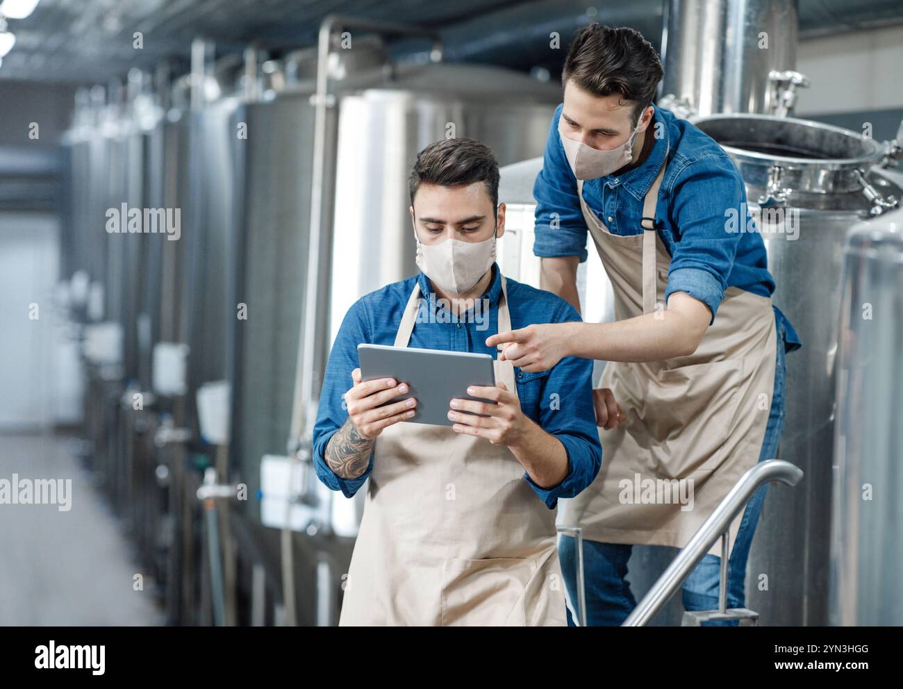 Brewery workers enter data at tablet and operate equipment Stock Photo ...