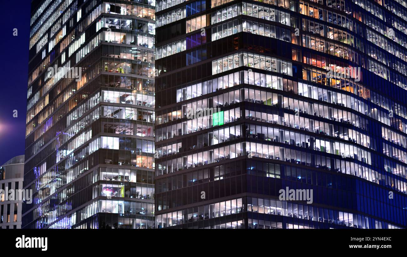 Office building in the evening with lightened workspaces. Modern ...