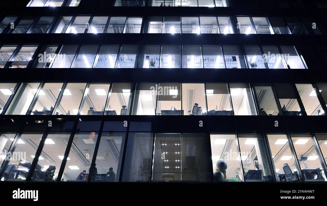 Office building in the evening with lightened workspaces. Modern ...