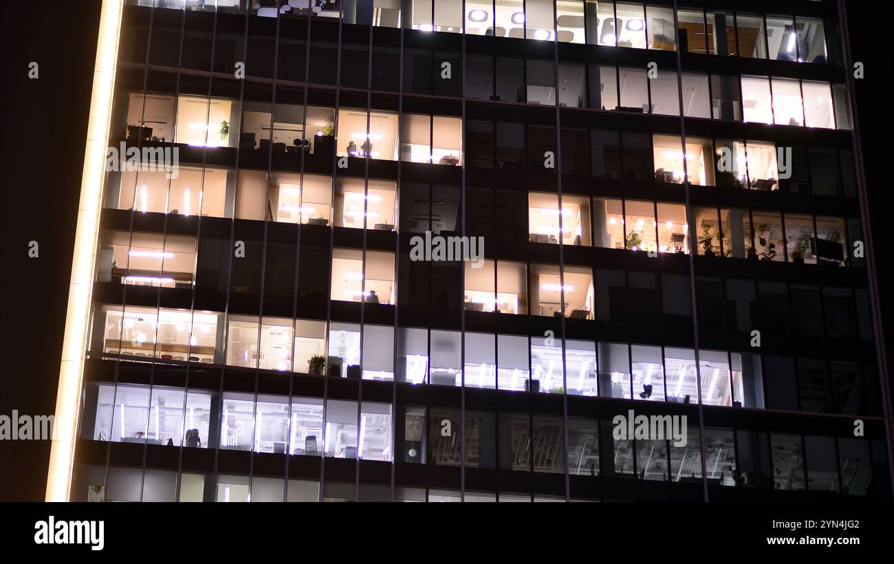 Office building in the evening with lightened workspaces. Modern ...