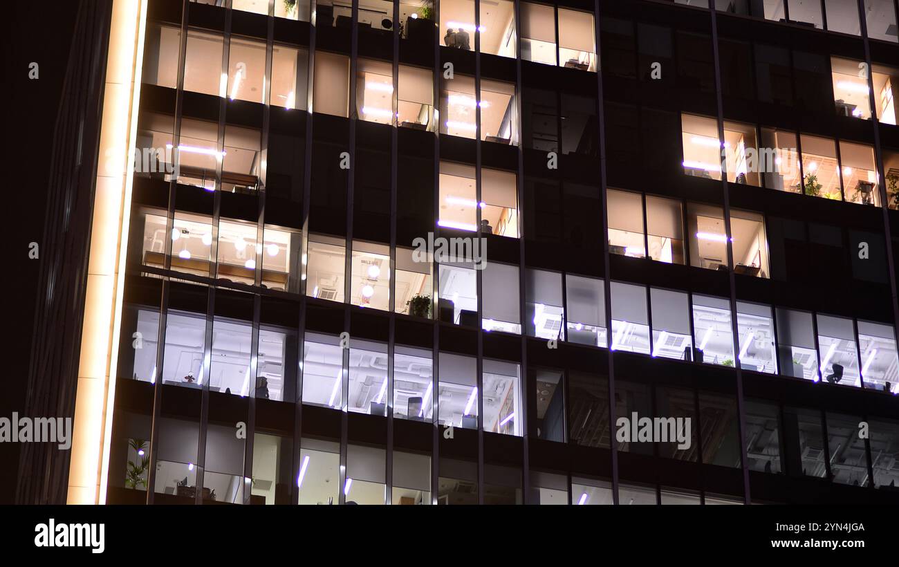Office building in the evening with lightened workspaces. Modern ...