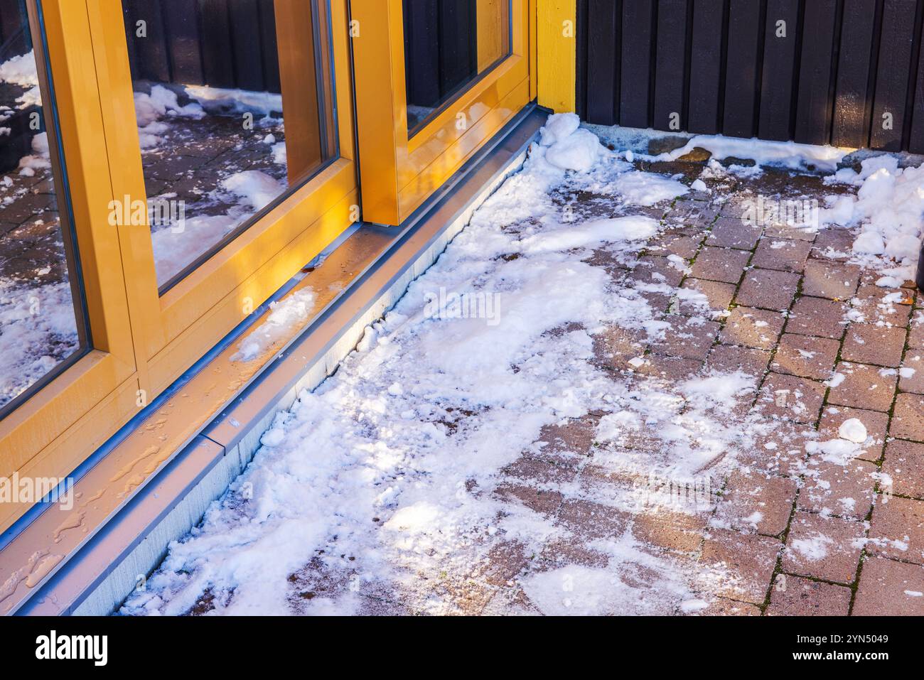 Yellow-framed glass door with snow and ice on doorstep and brick ...