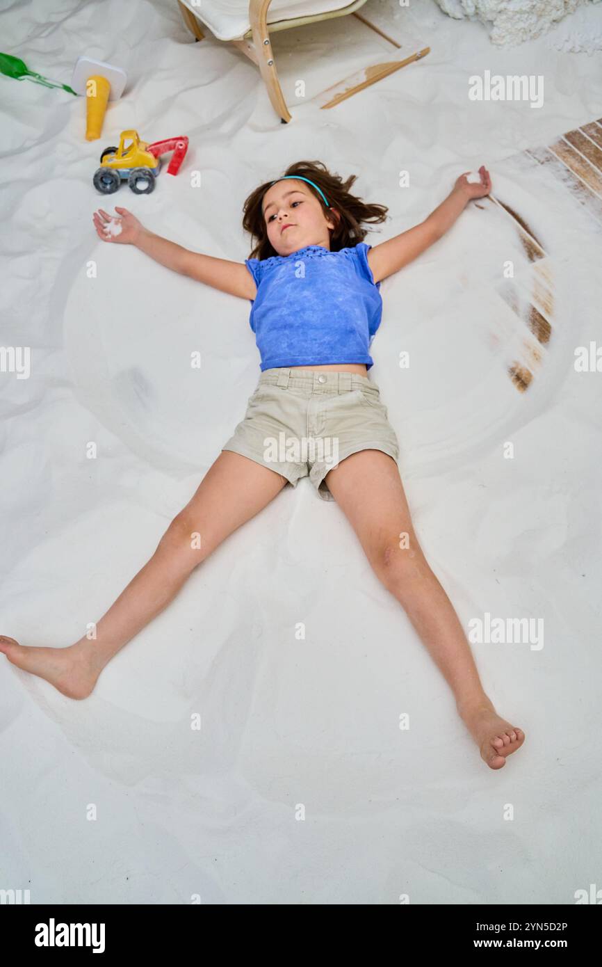 Girl making sand angels in an indoor play area Stock Photo - Alamy