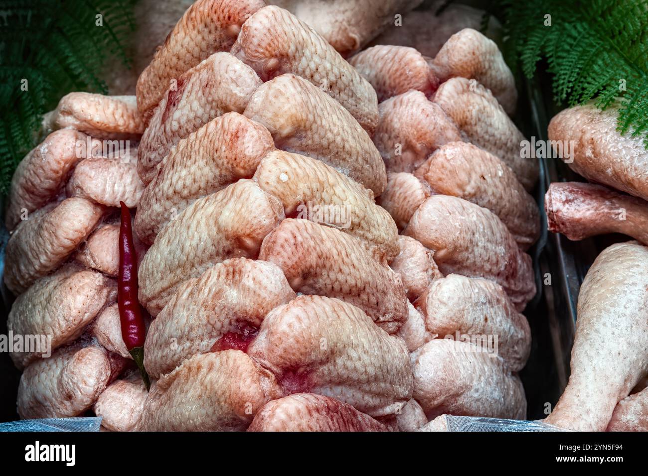 Chilled raw chicken legs with skin in butcher shop display case, top ...