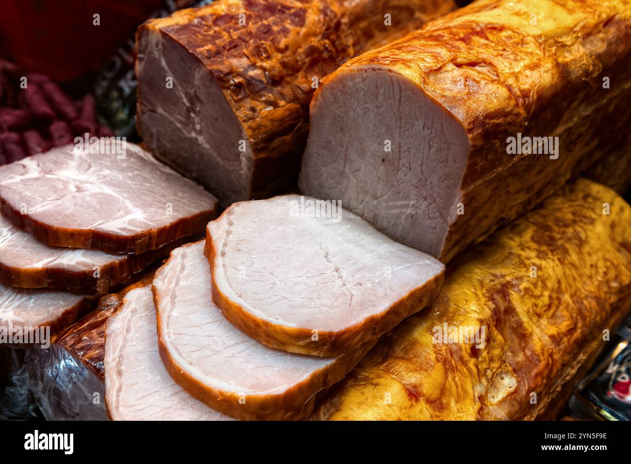 Various smoked pork hams in glass display case of butcher shop, top ...