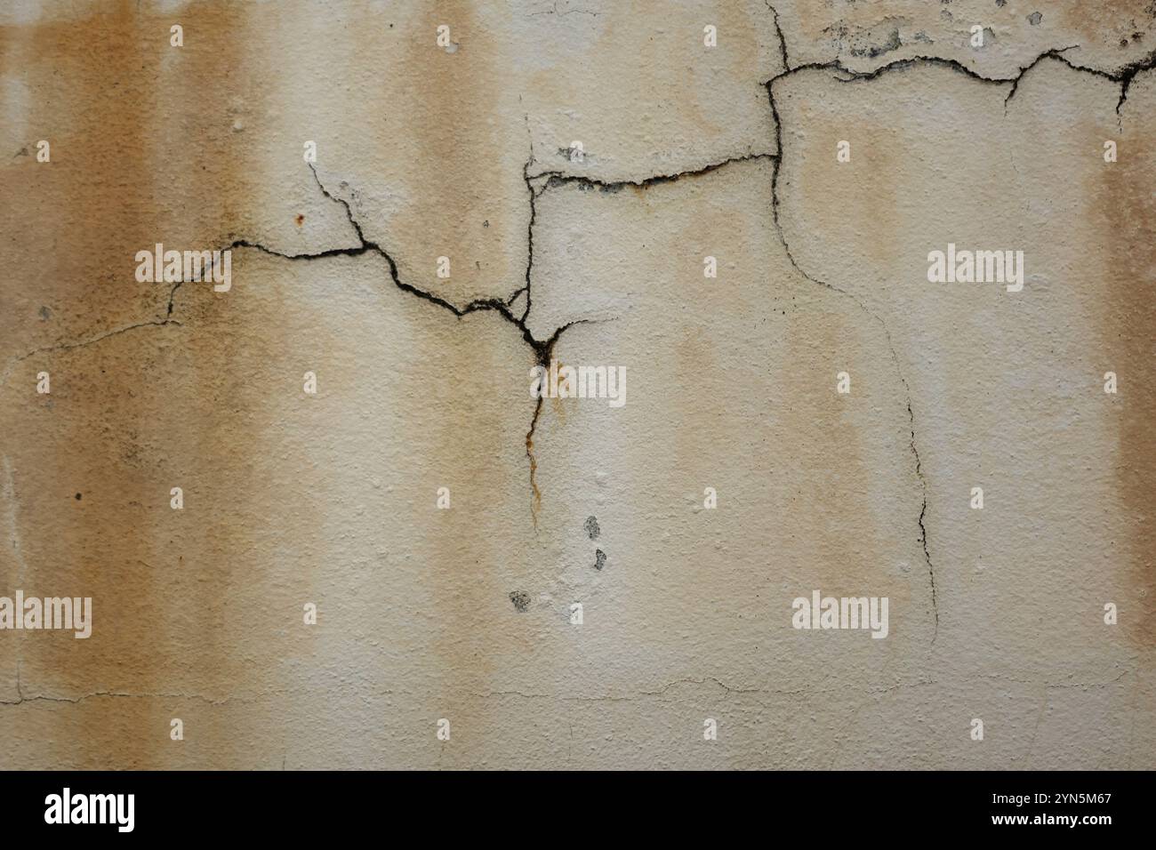 The wall displays extensive cracks and peeling paint, suggesting age and neglect in a weathered ...