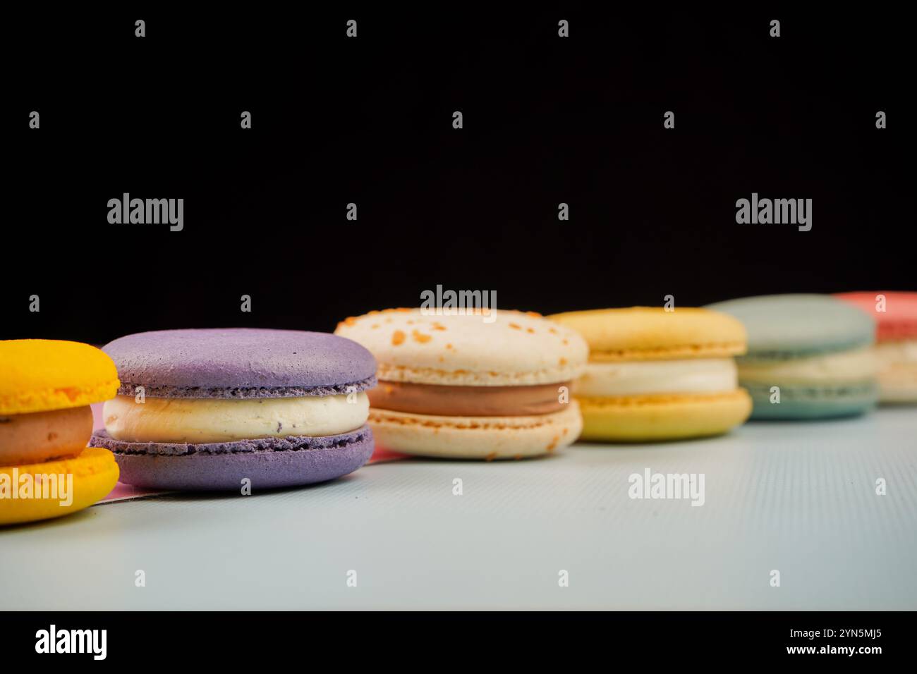 Close-up of colorful macarons lined up against a soft blue background ...