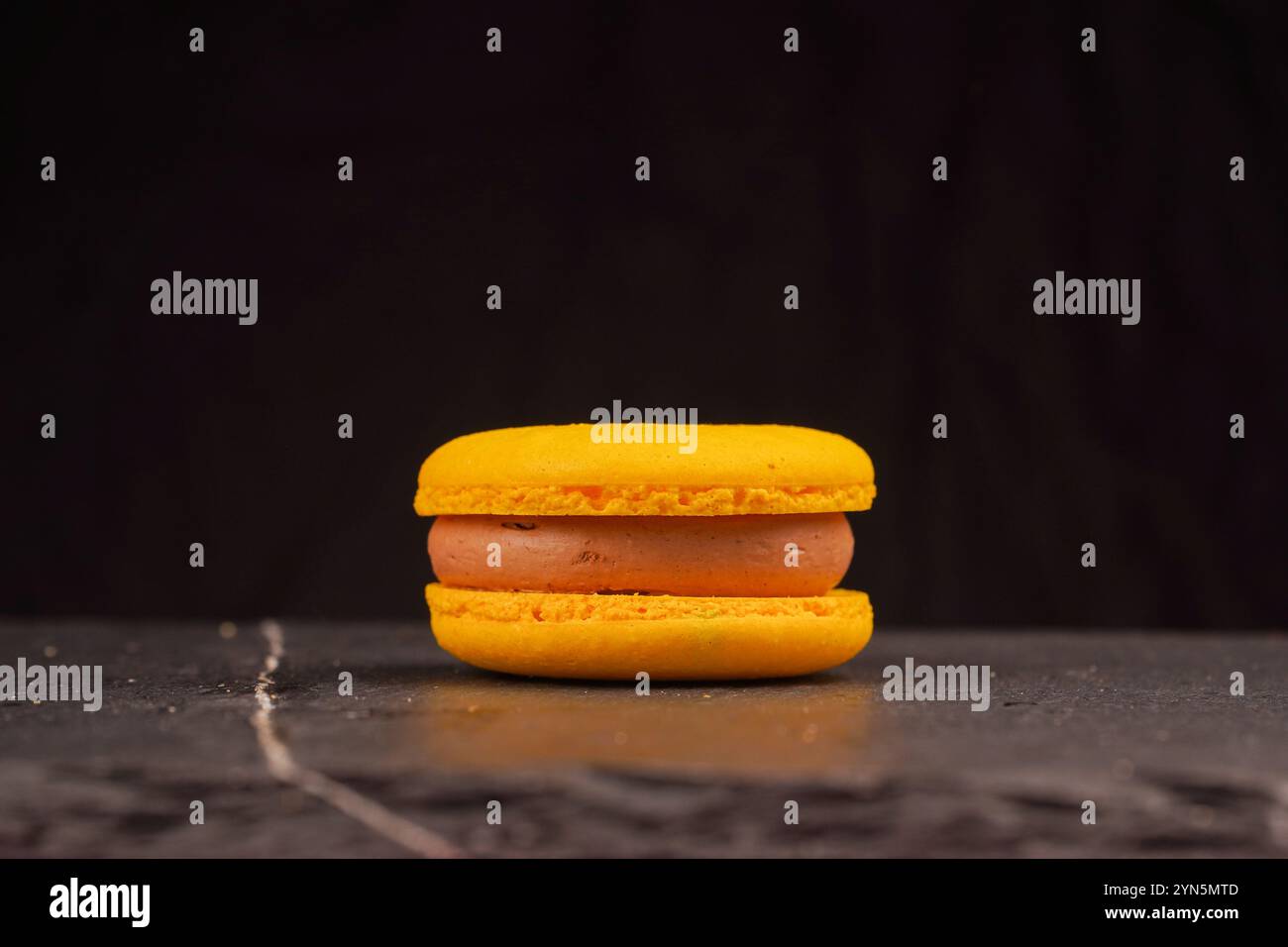 Pastel color macarons, placed on a black background. Yellow macarons ...