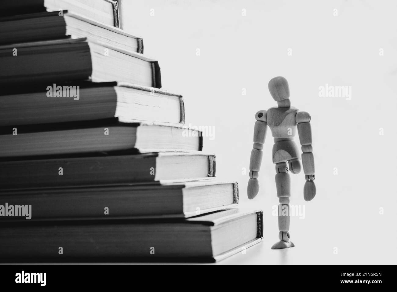 Wooden one-legged man and books as steps up, overcoming obstacles ...