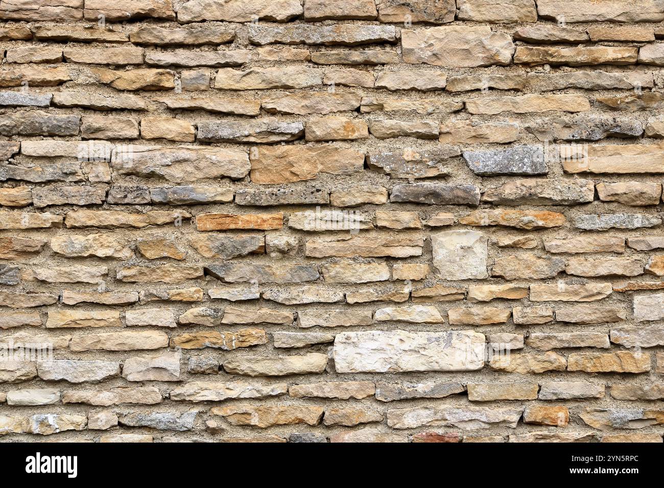 a yellow beige sand color stone brick vertical wall Stock Photo - Alamy