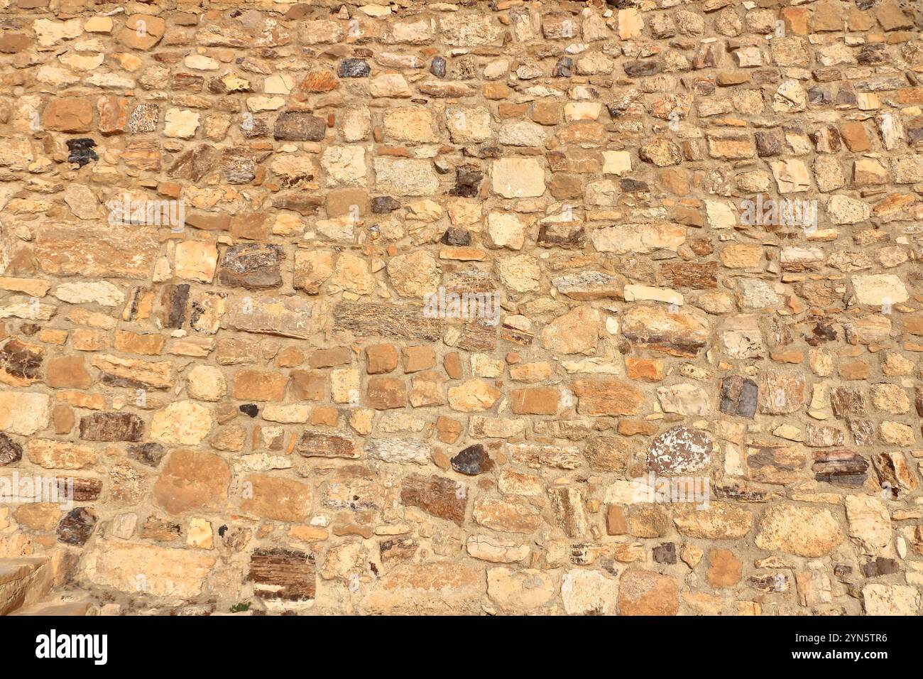 a yellow beige natural stone wall of different sized stones ...