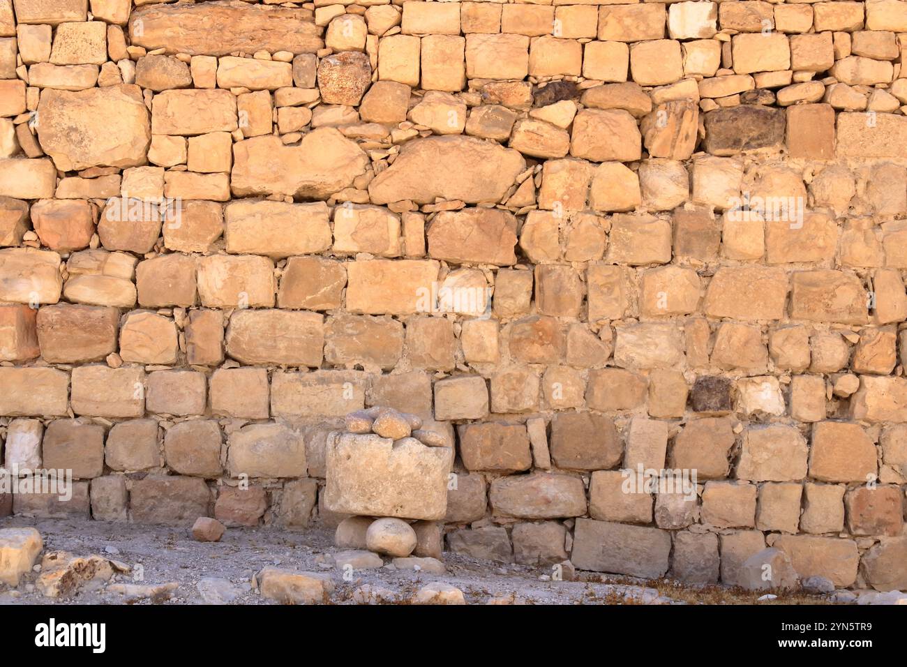 a yellow beige natural stone wall of different sized stones ...