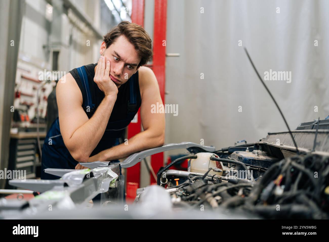 Disappointed automotive mechanic male in grease-stained uniform, leans ...