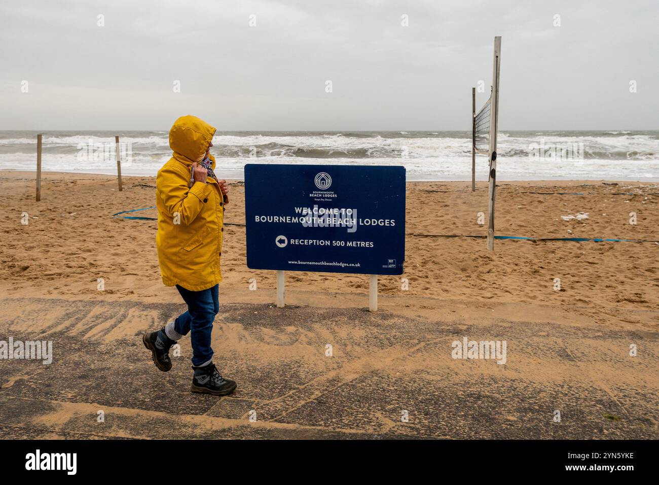 Woman walking along seafront during Storm Bert, Boscombe, Dorset, UK ...