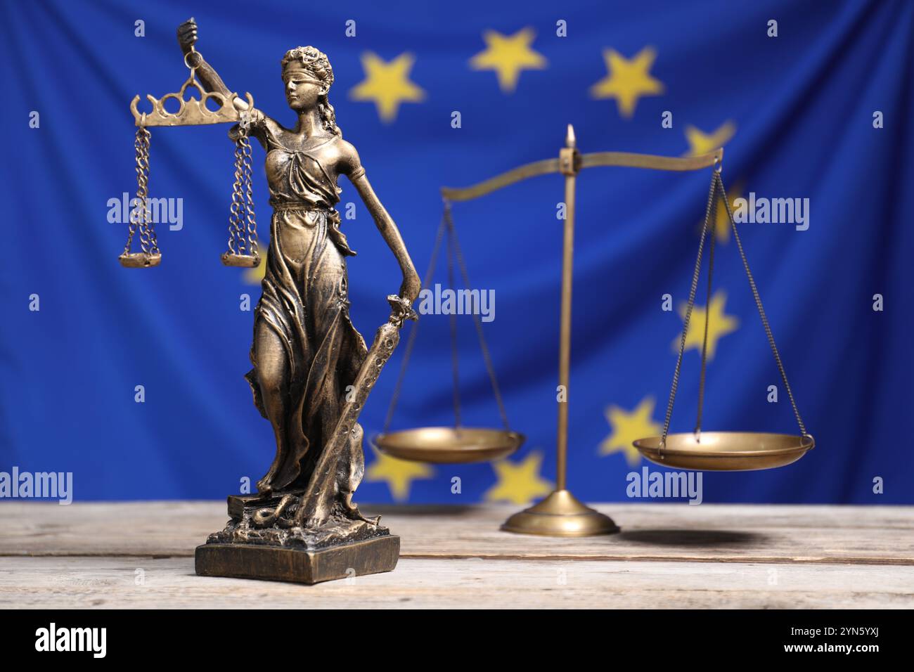 Figure of Lady Justice and scales on wooden table against European ...