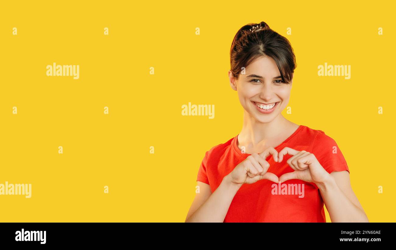 Heart gesture. Smiling woman in red showing romantic love sign with ...