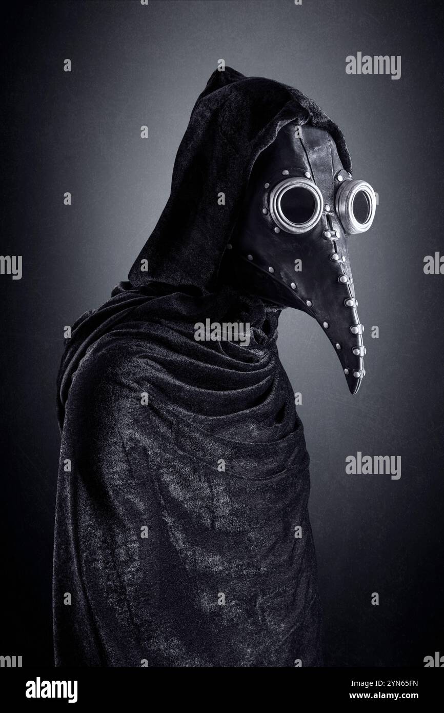 Plague doctor in hooded cloak at night over dark misty background Stock Photo - Alamy