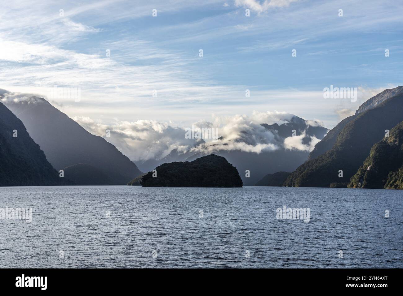 Sun rising over Doubtful Sound, Clouds hanging low on the mountains ...