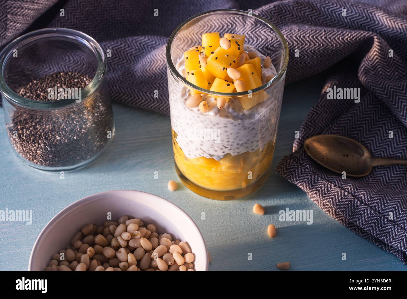 Pudding made from chia seeds, mango puree, pine nuts and yogurt on the table with a spoon and a ...