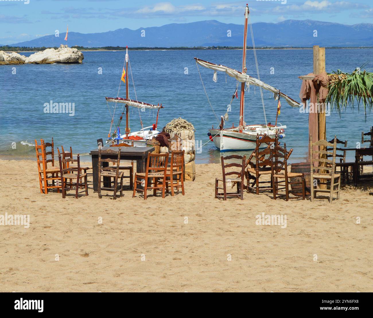Antique chairs and tables on the beach with fishing boats in the ...
