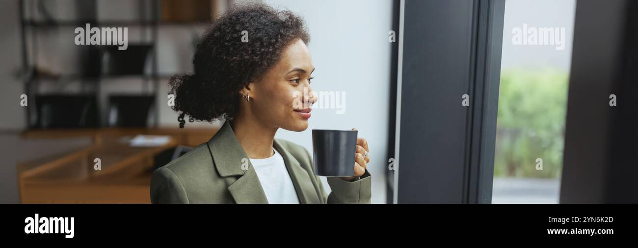 A woman in formal wear sips coffee, gazes out window Stock Photo - Alamy
