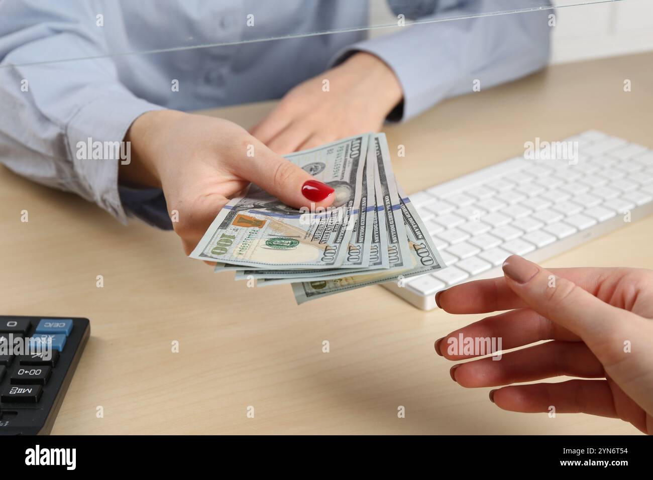 Cashier giving dollar banknotes to client at table in money exchange ...