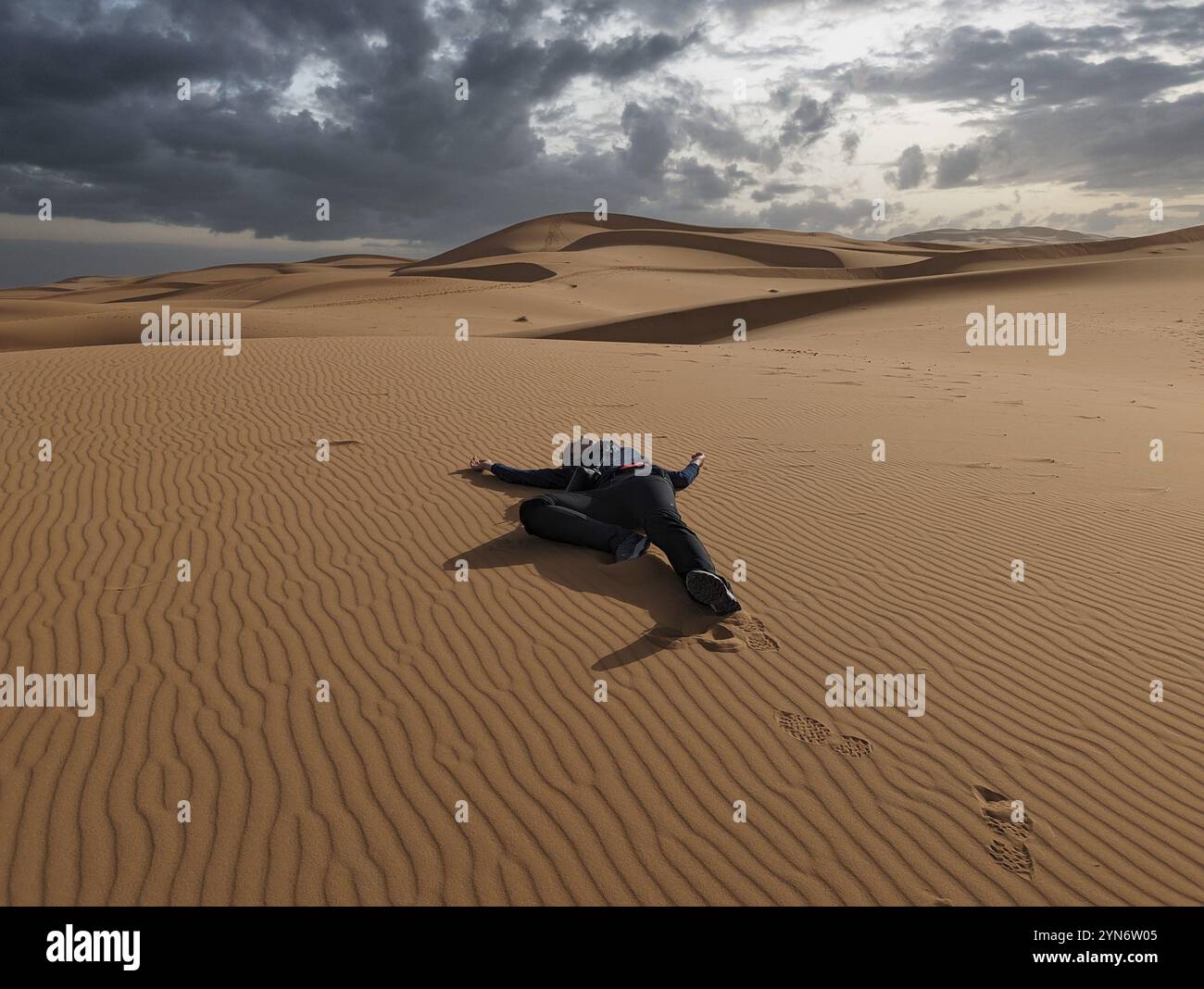 A person pretending to lay dead in the Erg Chebbi desert in Morocco ...
