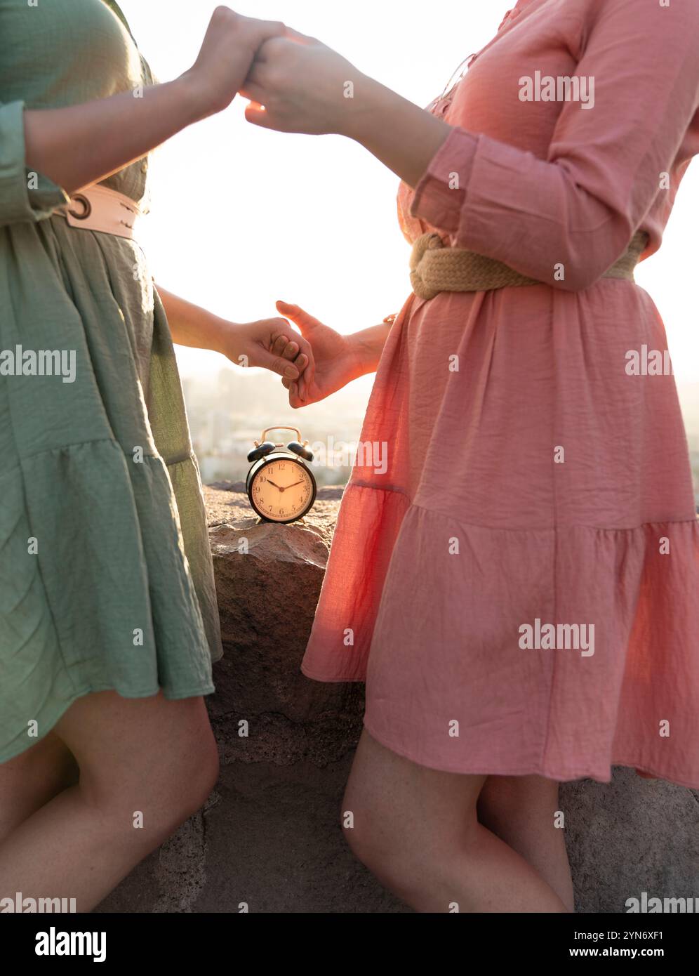 Two woman holding alarm clock outdoors. friendship and togetherness ...