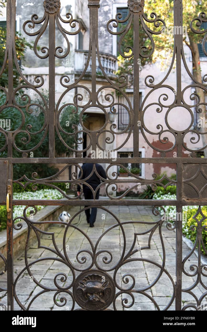 Man with Dog going for a walk, view through an Iron Gate, Venice, Italy ...