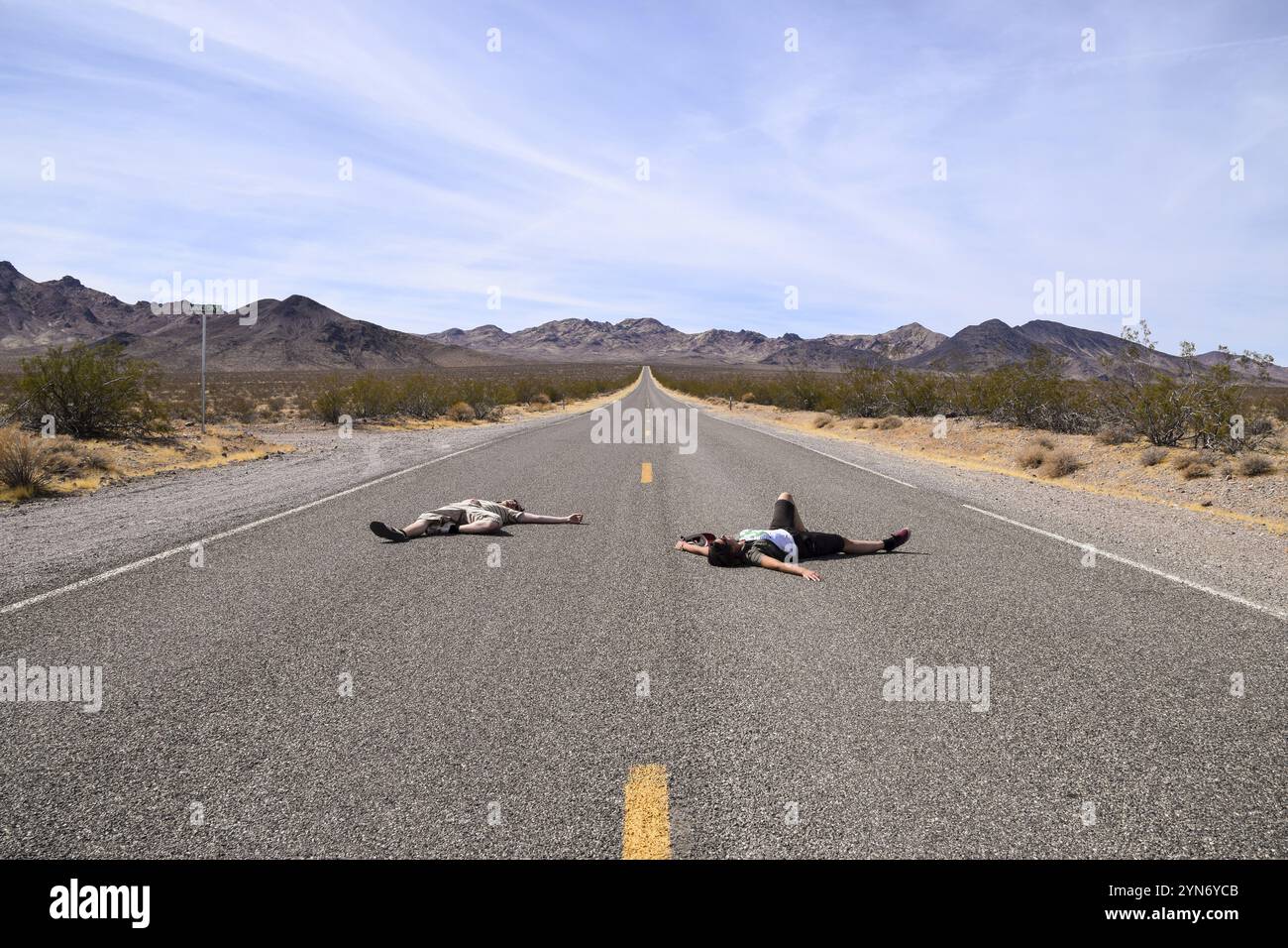 Two people pretending to lay dead on a highway in the Death Valley, USA ...