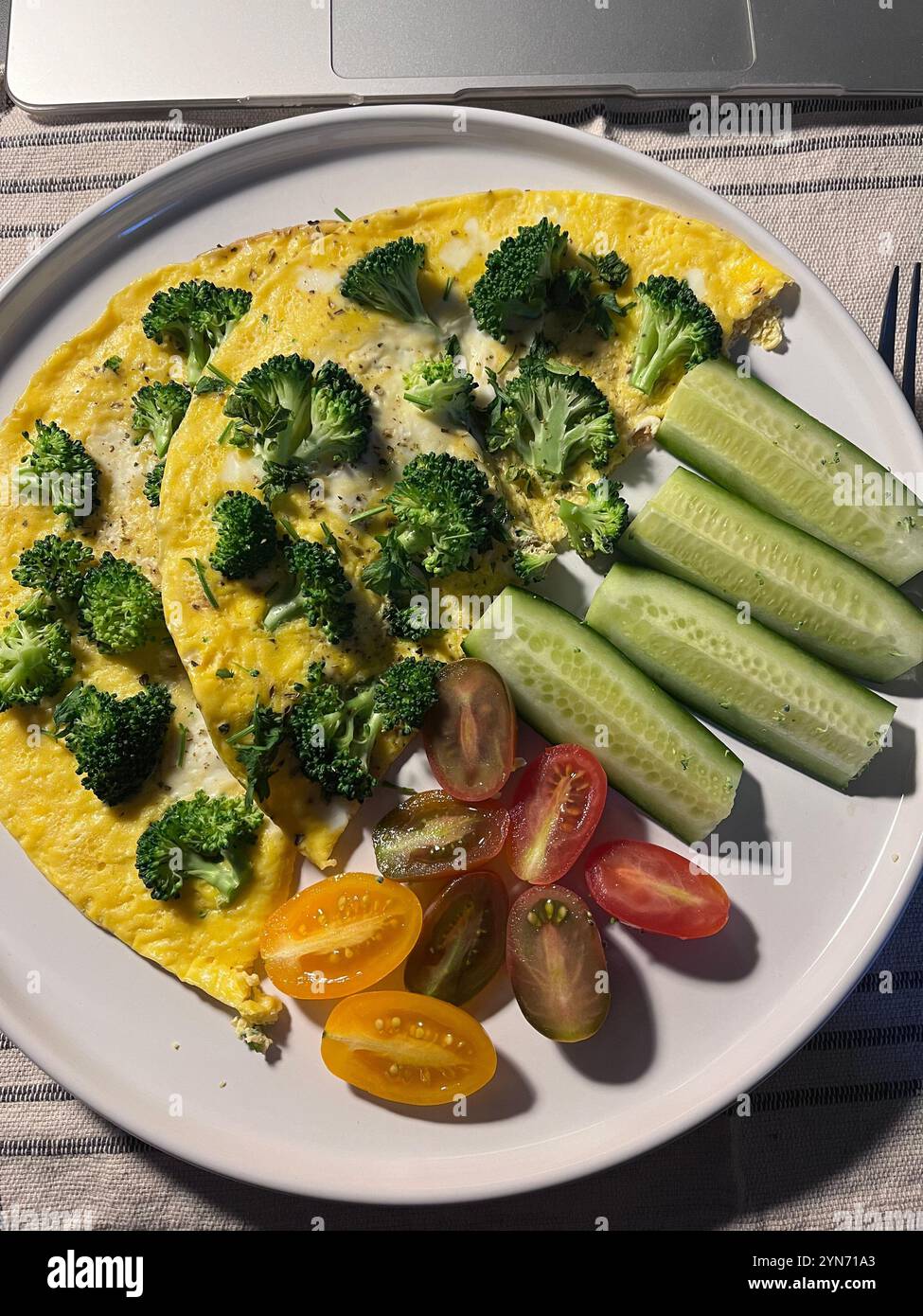 Two fluffy omelets filled with broccoli are served on a plate alongside ...