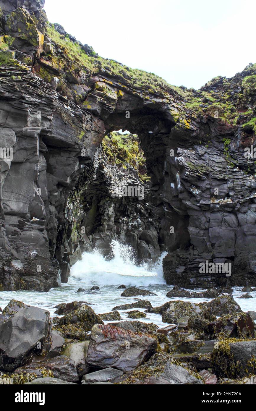 Natural arch at the coast of Hellnar, water clashing through the arch ...