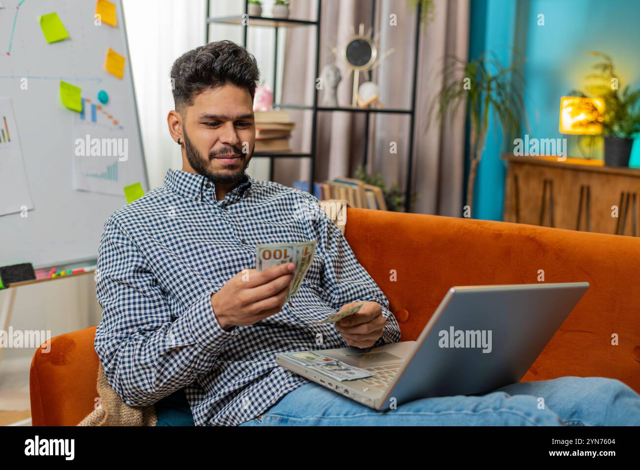 Planning budget. Rich happy Indian man counting money cash use laptop ...