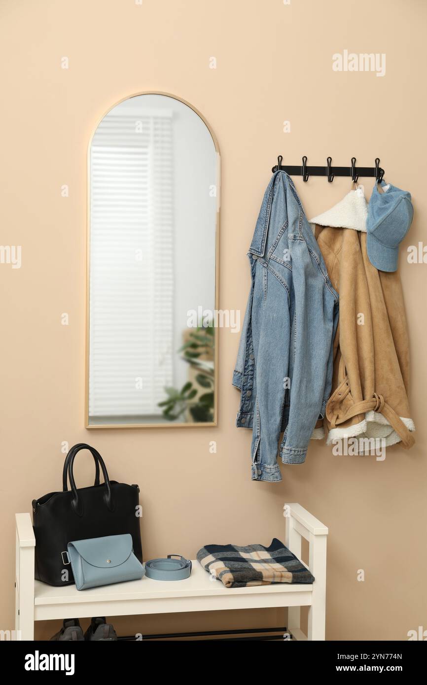 Coat rack with clothes, mirror and shoe storage bench in hallway ...
