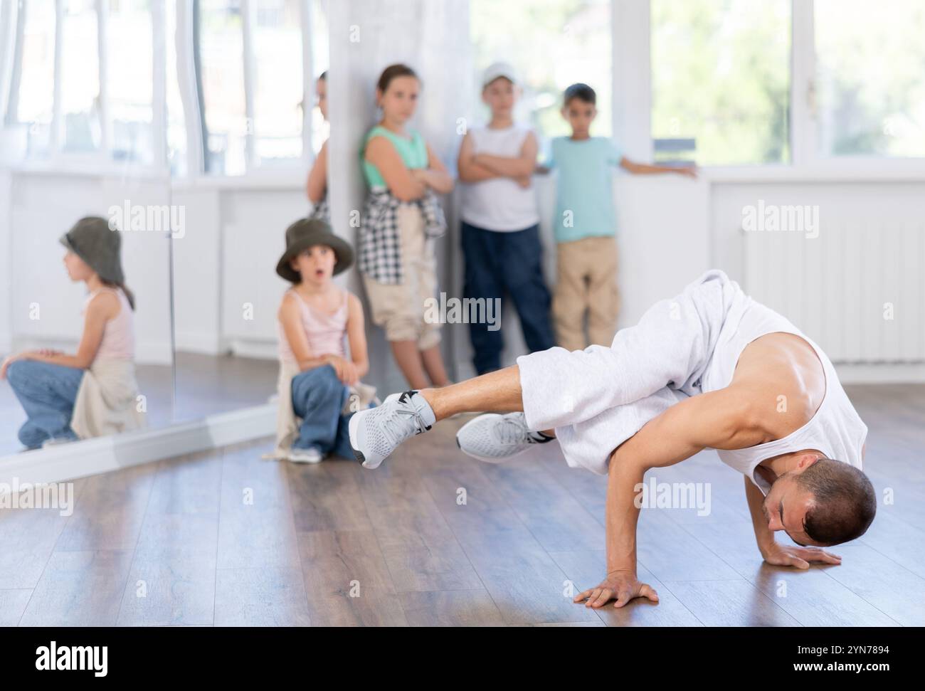 Young breakdancer demonstrating dance moves to group of tweens in ...