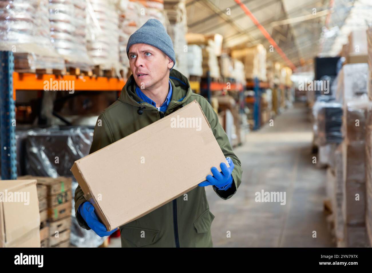 Warehouse worker carrying large box of goods in arehouse Stock Photo ...
