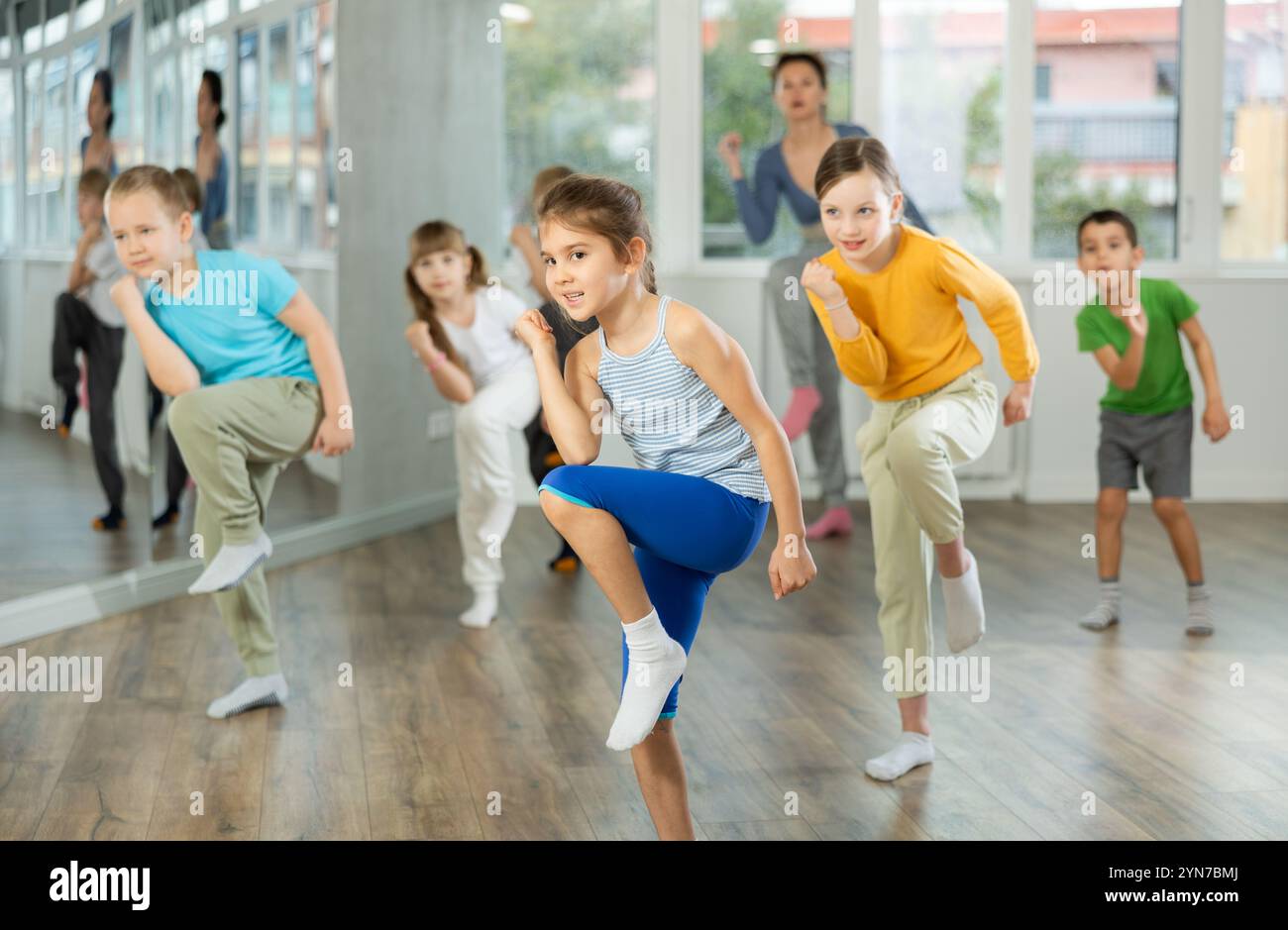 Positive juvenile girl engaged in Rock 'n' Roll dance in training room ...