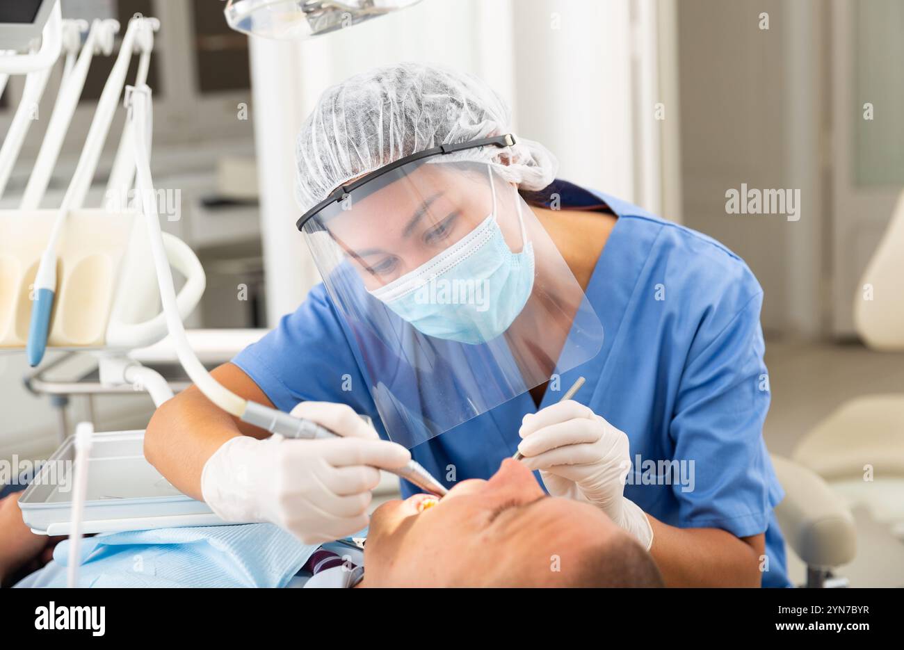 Female dentist drilling tooth to male patient Stock Photo - Alamy