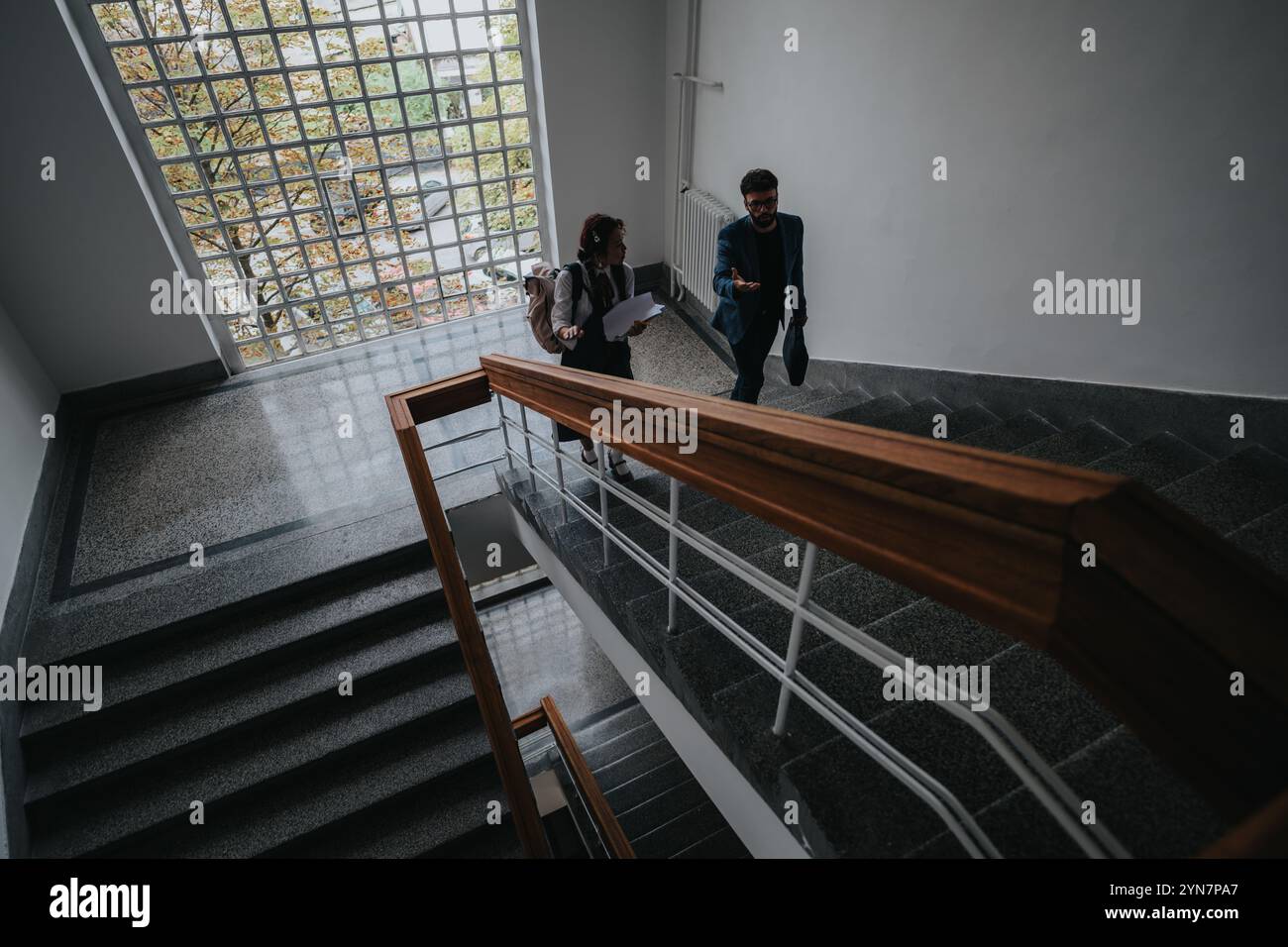 Students walking up stairs consulting professor with documents Stock ...