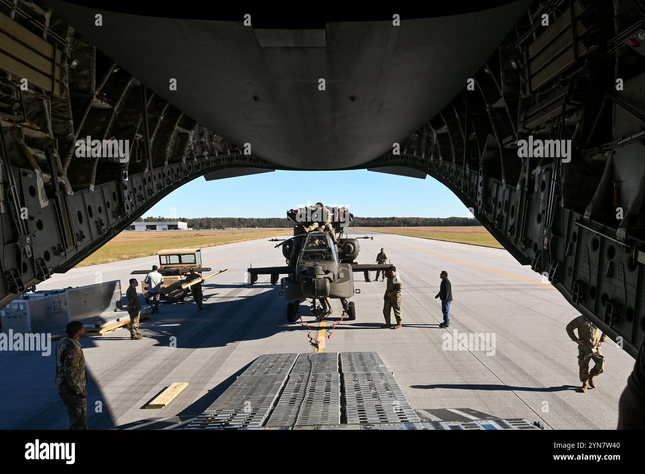 U.S. Army personnel prepare to load A Boeing AH-64 Apache helicopter ...