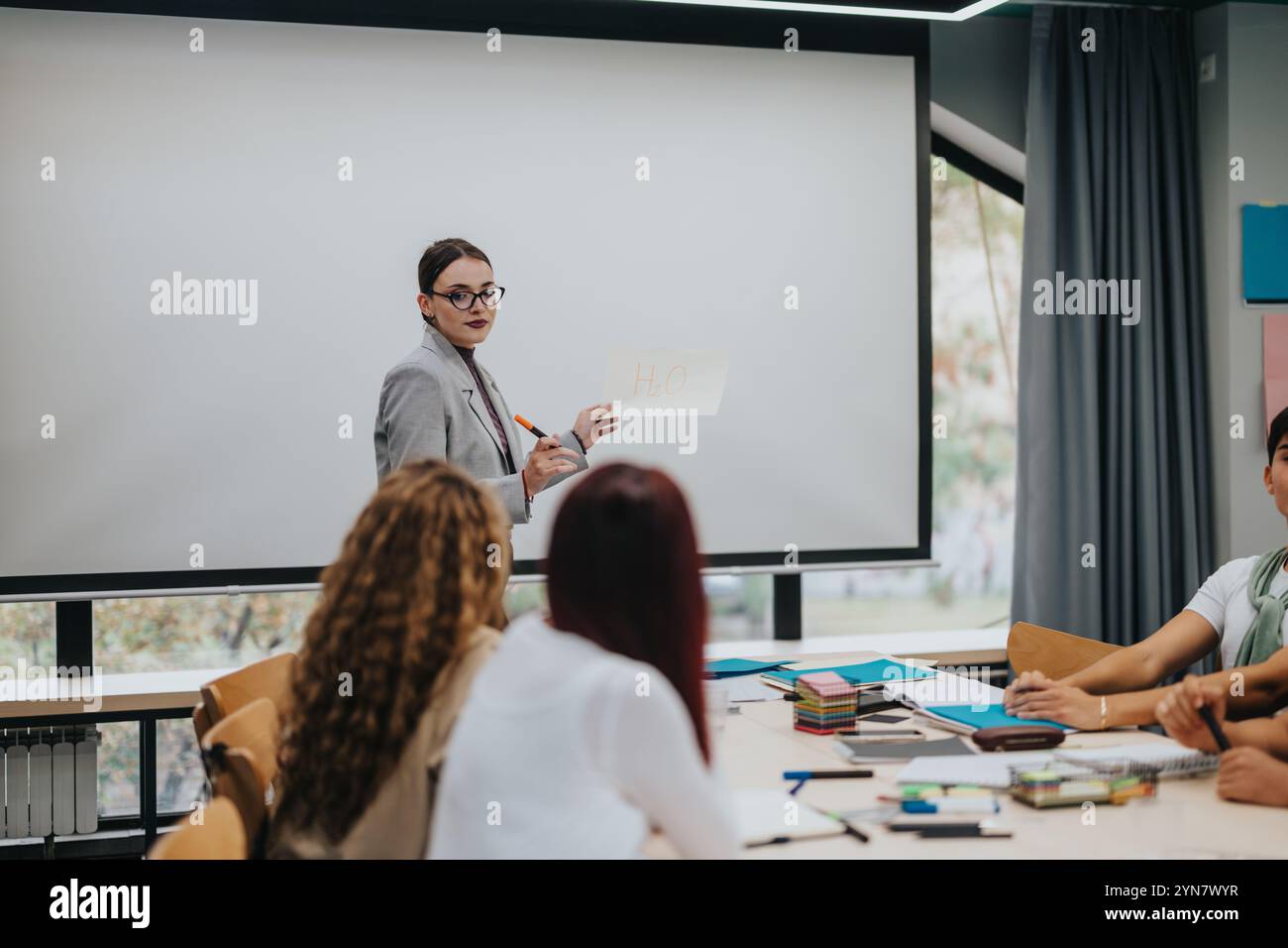 Teacher explaining chemistry concept in classroom setting with students ...