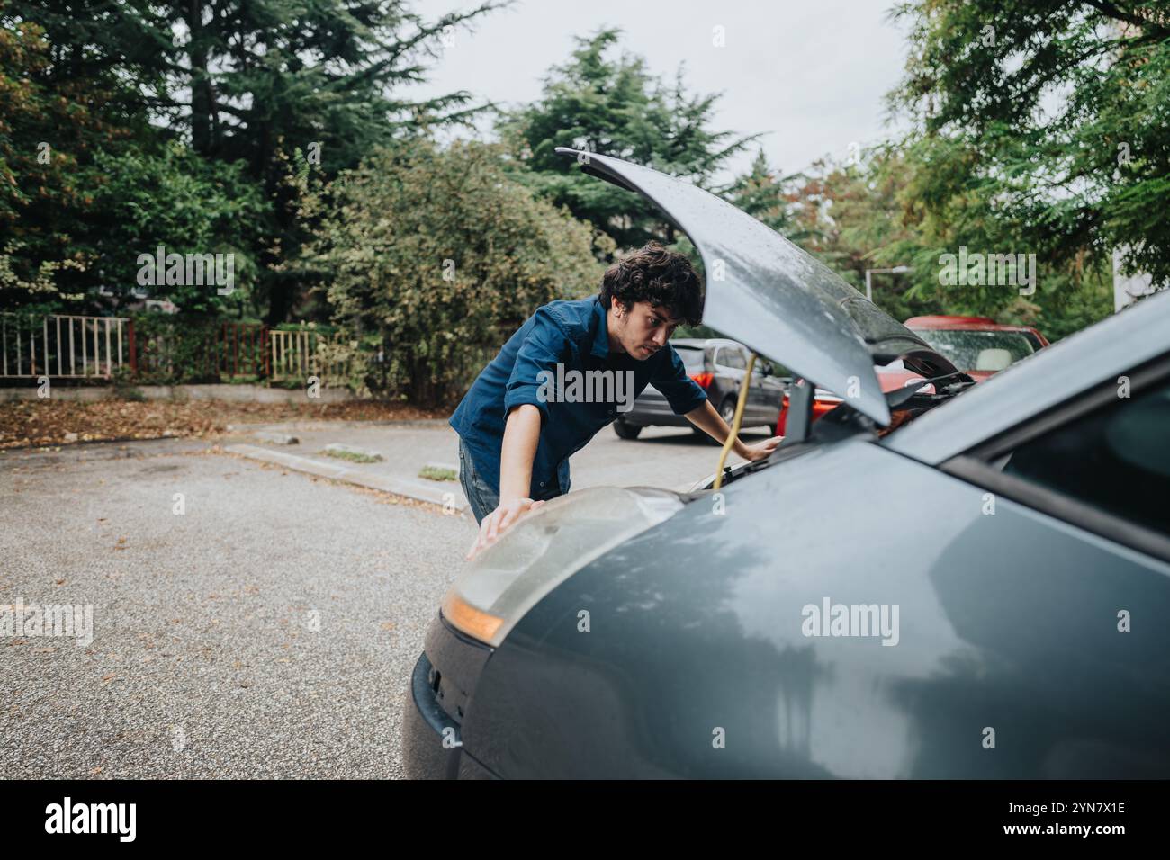 Man inspecting car engine with hood open in parking area Stock Photo ...