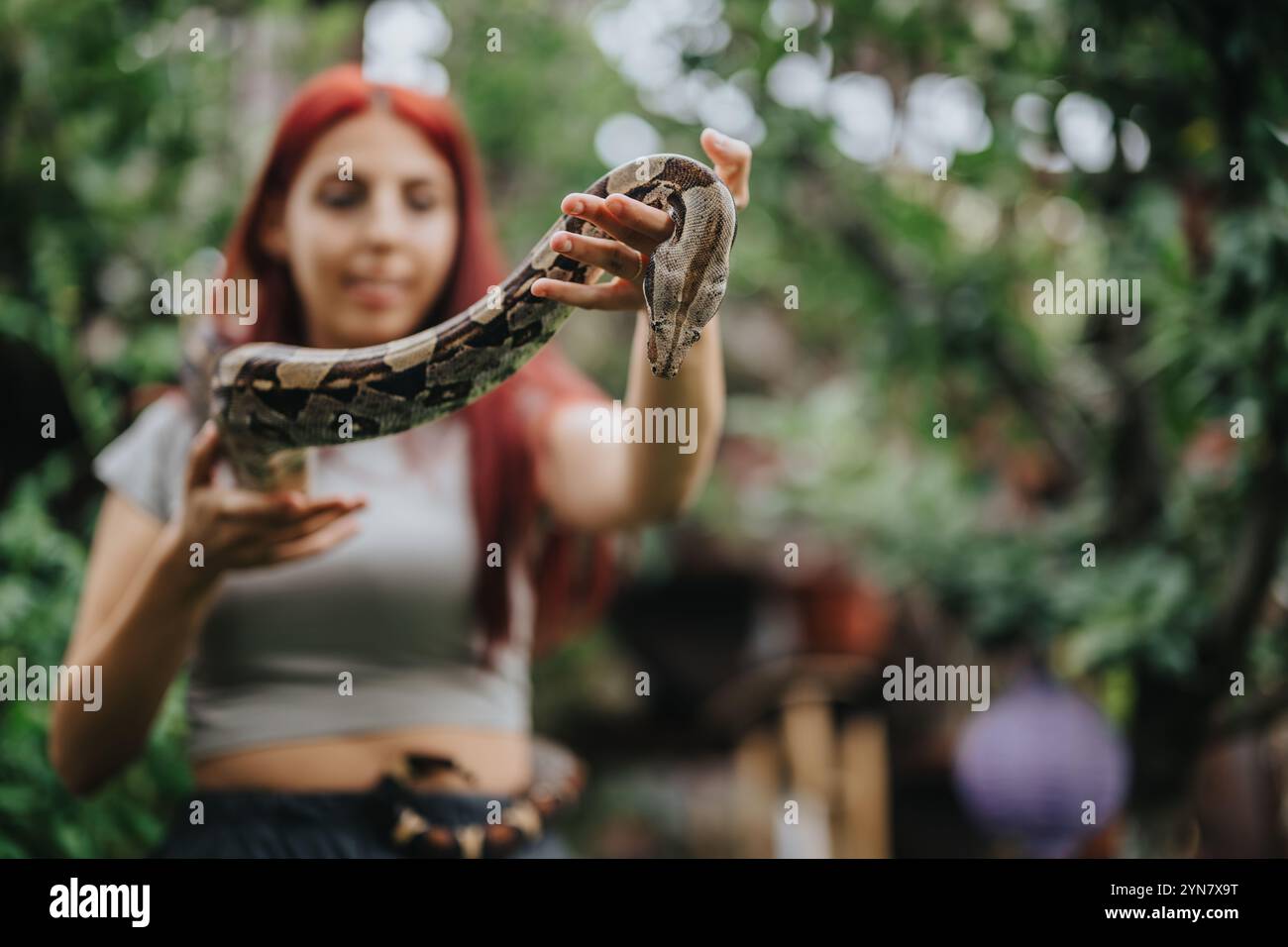 Girl holding a snake in a lush garden setting outdoors Stock Photo - Alamy