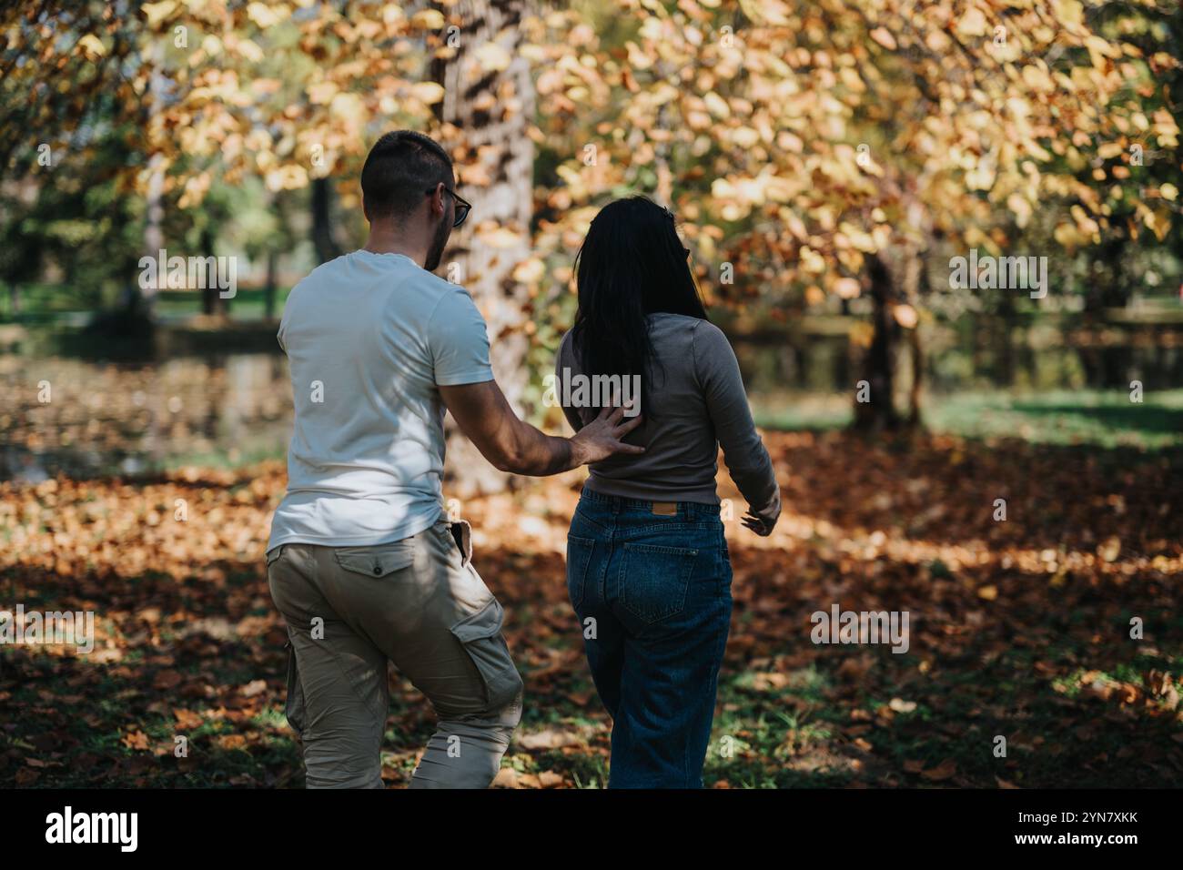 Romantic couple walking in autumn park with colorful leaves around ...